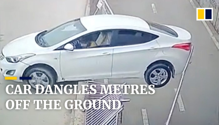Car dangles metres off the ground after driver reversed through ...